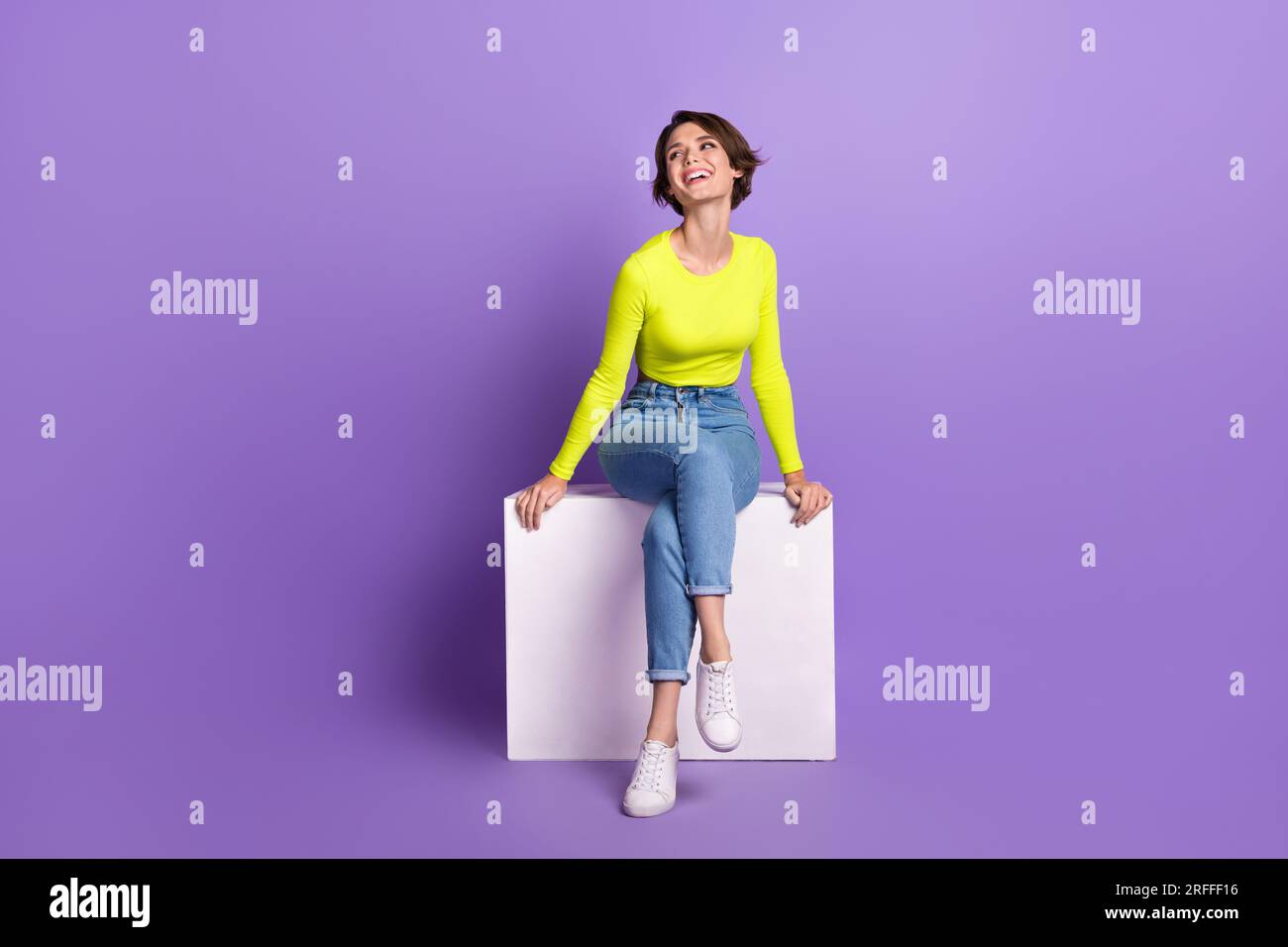Full body portrait of stunning positive minded lady sit cube podium ...