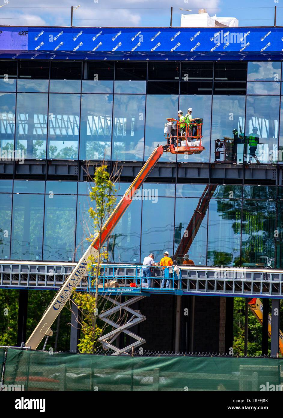 Construction workers installing glass panels on a new office building ...