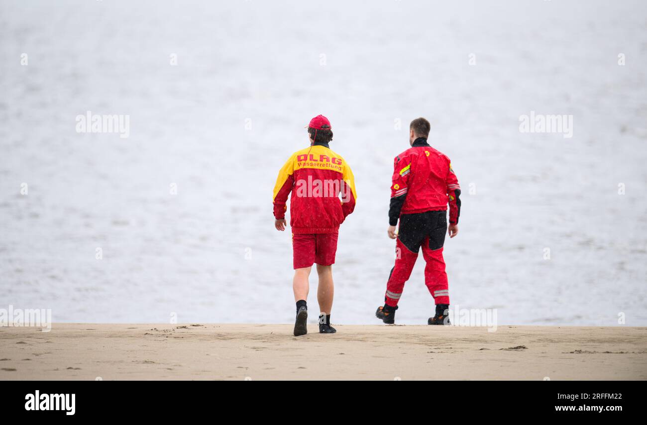 Hamburg, Germany. 03rd Aug, 2023. Two DLRG staff members walk along the ...