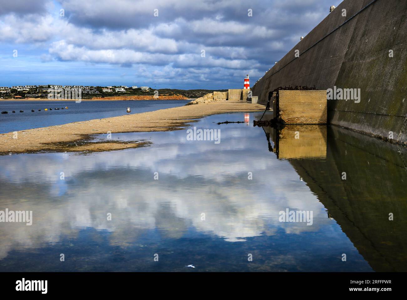 Concrete blocks on a puddle of water with reflections in the port of ...