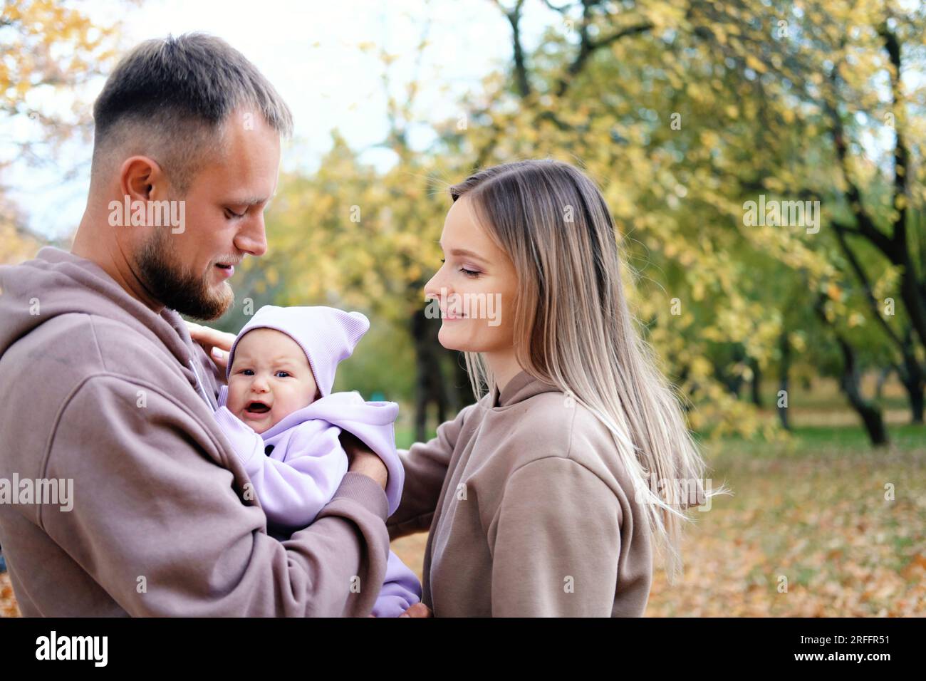 Parents on a walk with a baby in the autumn park. The baby is crying ...