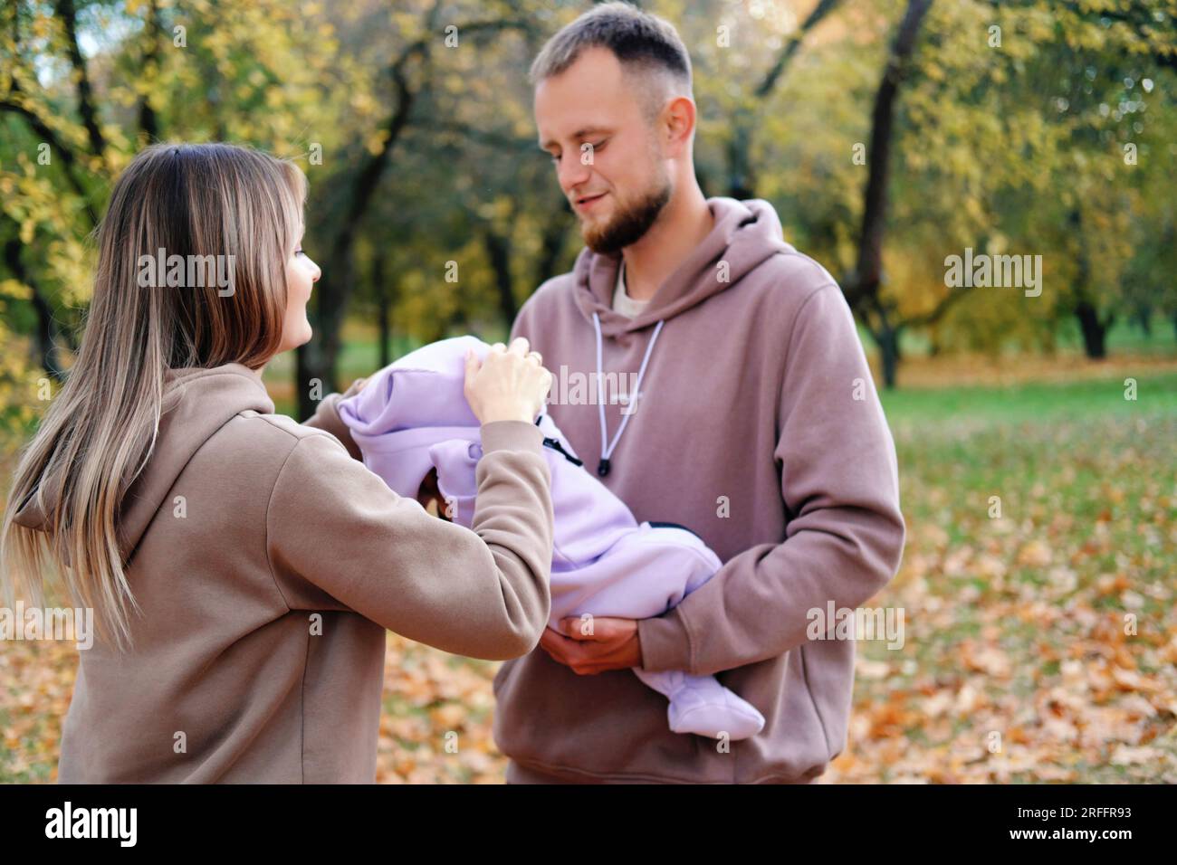 Parents on a walk with a baby in the autumn park. The baby is crying ...