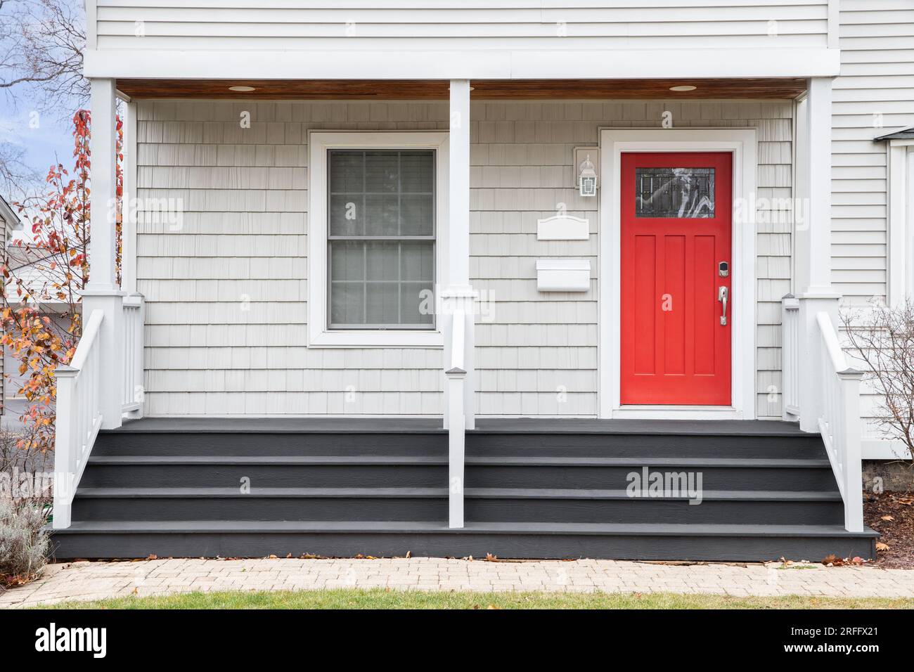 Detail of a front porch of a white home with grey steps leading up to a ...