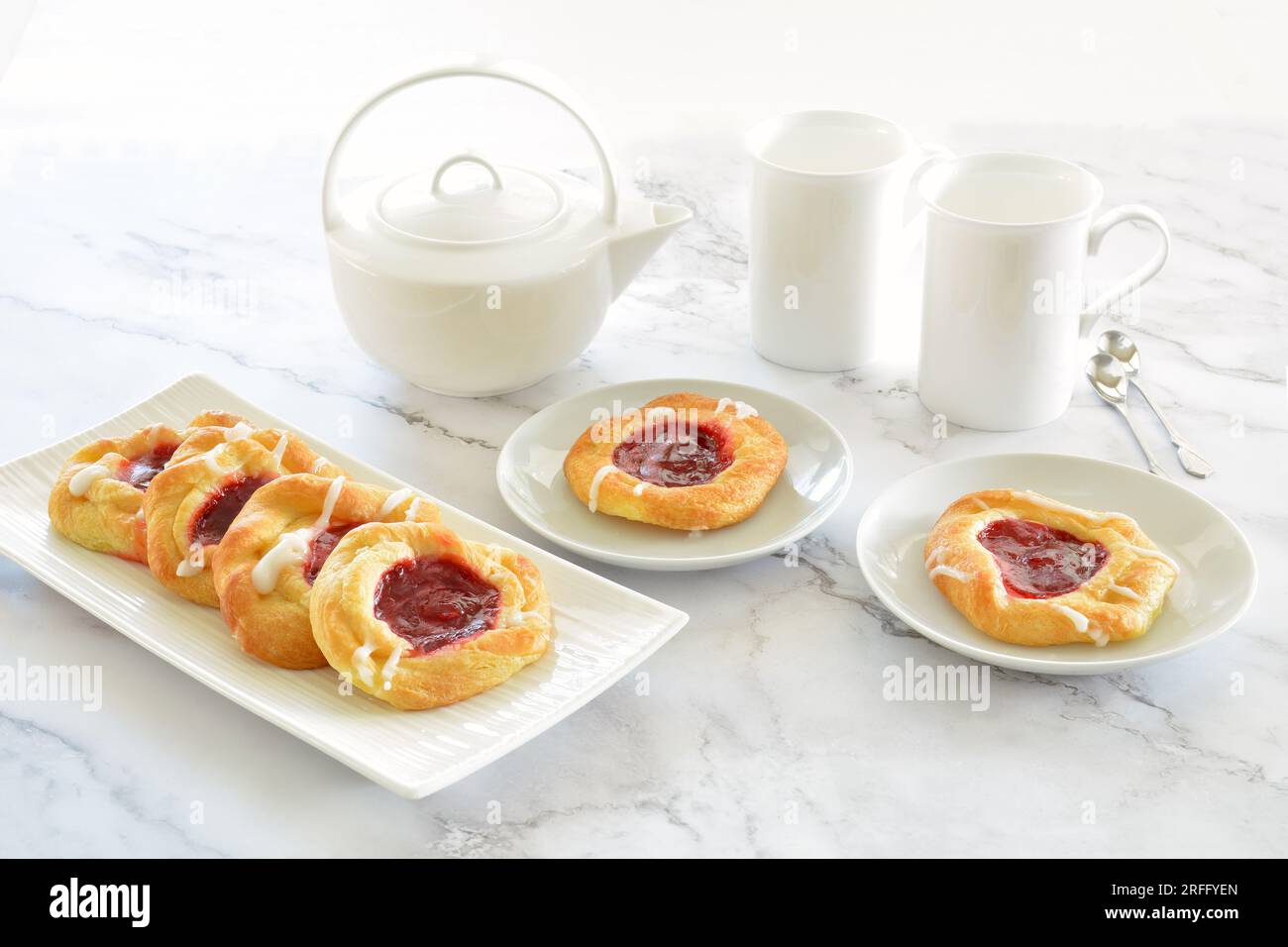 Fresh baked raspberry danish pastries on white plates with white teapot ...