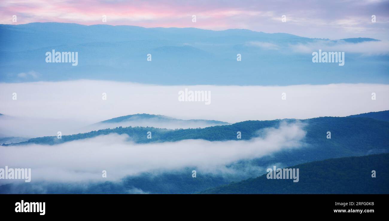 view of green mountain forested hills in fog. dramatic clouds above the ...