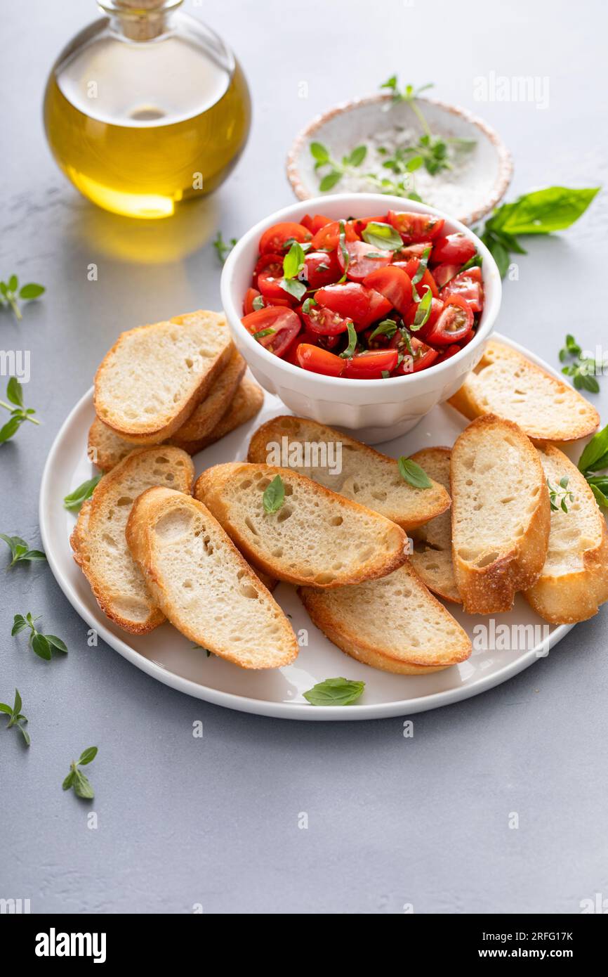 Making tomato basil bruschetta with toasted baguette and fresh herbs ...