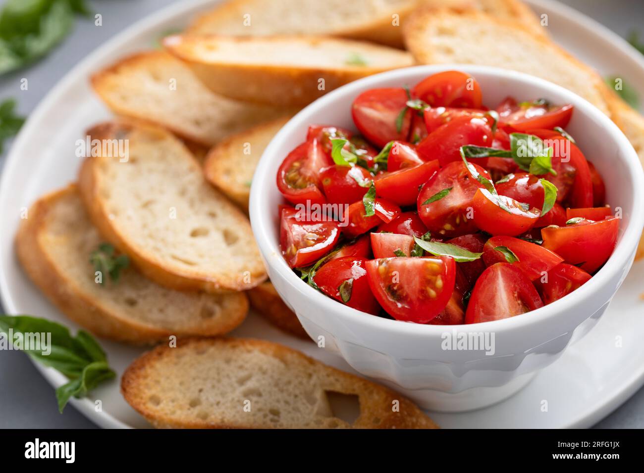 Making tomato basil bruschetta with toasted baguette and fresh herbs ...