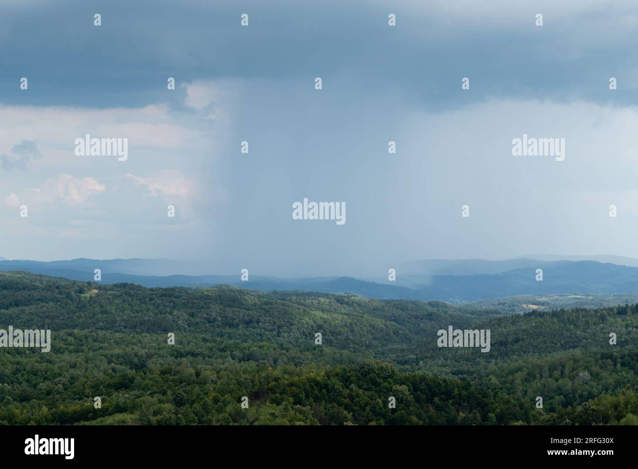 Cloudburst above hills overgrown in forests during summer, extreme ...