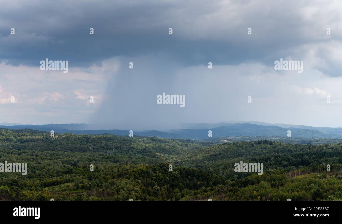 Cloudburst above hills overgrown in forests during summer, extreme ...