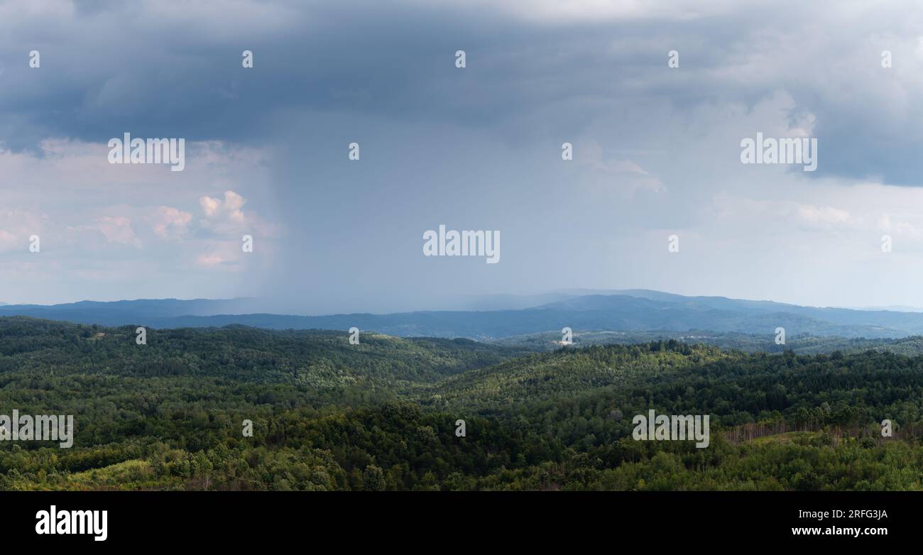 Cloudburst above hills overgrown in forests during summer, extreme ...