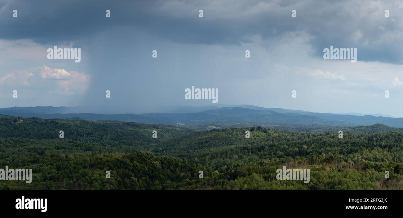 Cloudburst above hills overgrown in forests during summer, extreme ...