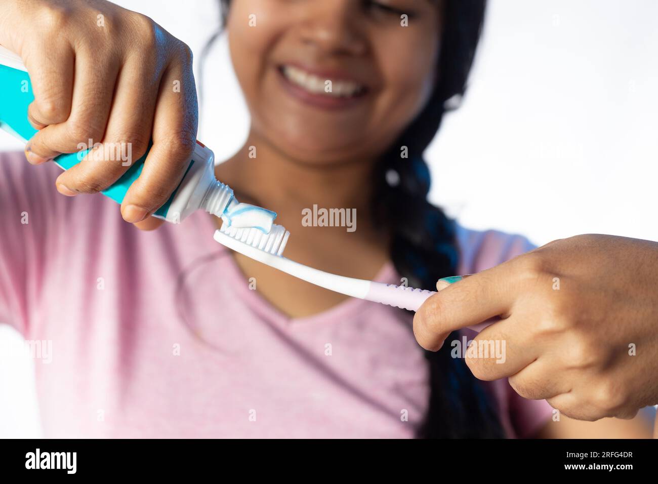 An Indian woman female girl applying toothpaste on toothbrush on white ...
