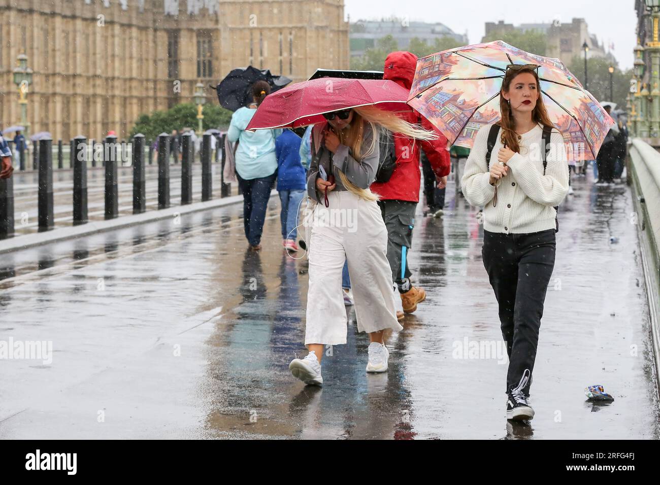 Women shelter under umbrellas in the rain in London. Weather forecasters are predicting more for ...