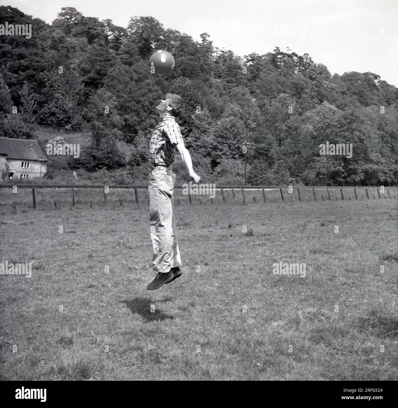 1960s, historical, summer fun, a man in a countryside field jumping off ...
