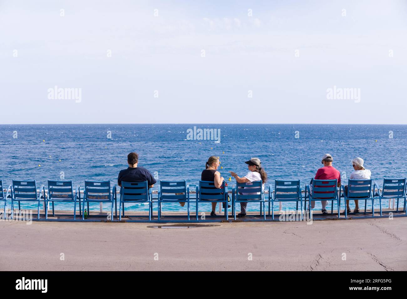 People on the famous blue chairs on the 'Promenade des Anglais' in Nice ...