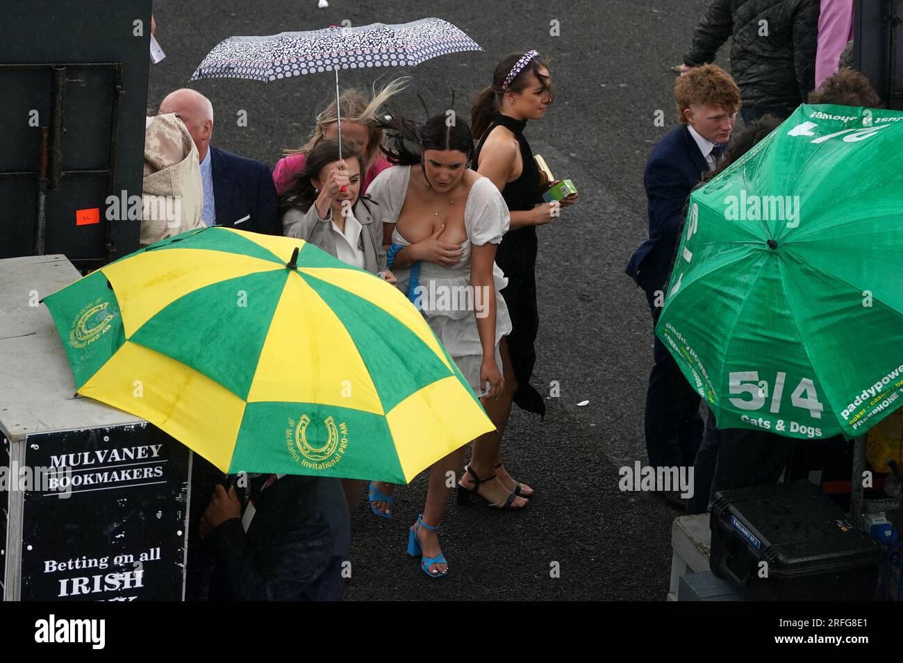 Racegoers shelter from the rain under an umbrella during day four of the Galway Races Summer ...