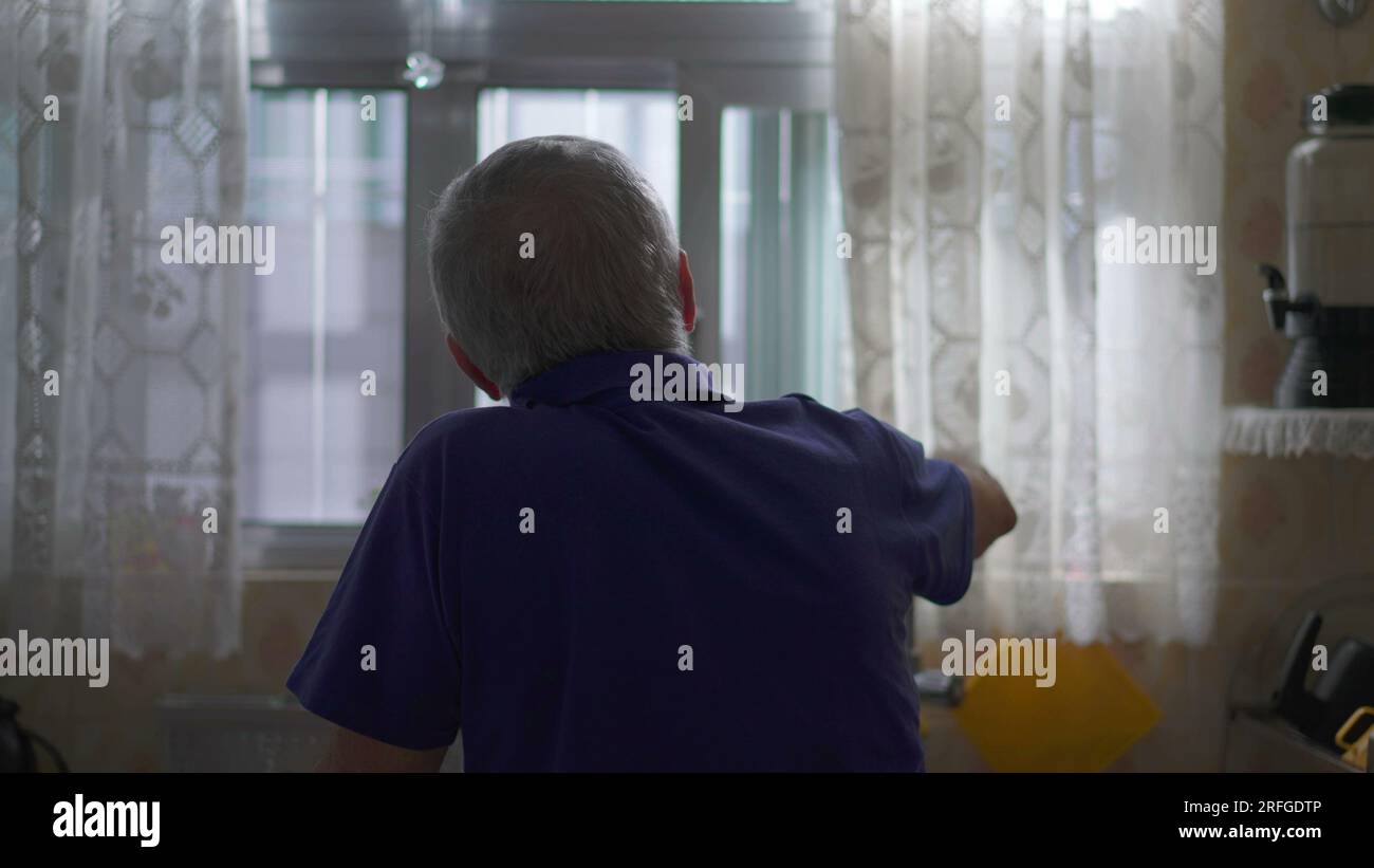 Back of elderly man looking out window view at home, opening curtains ...