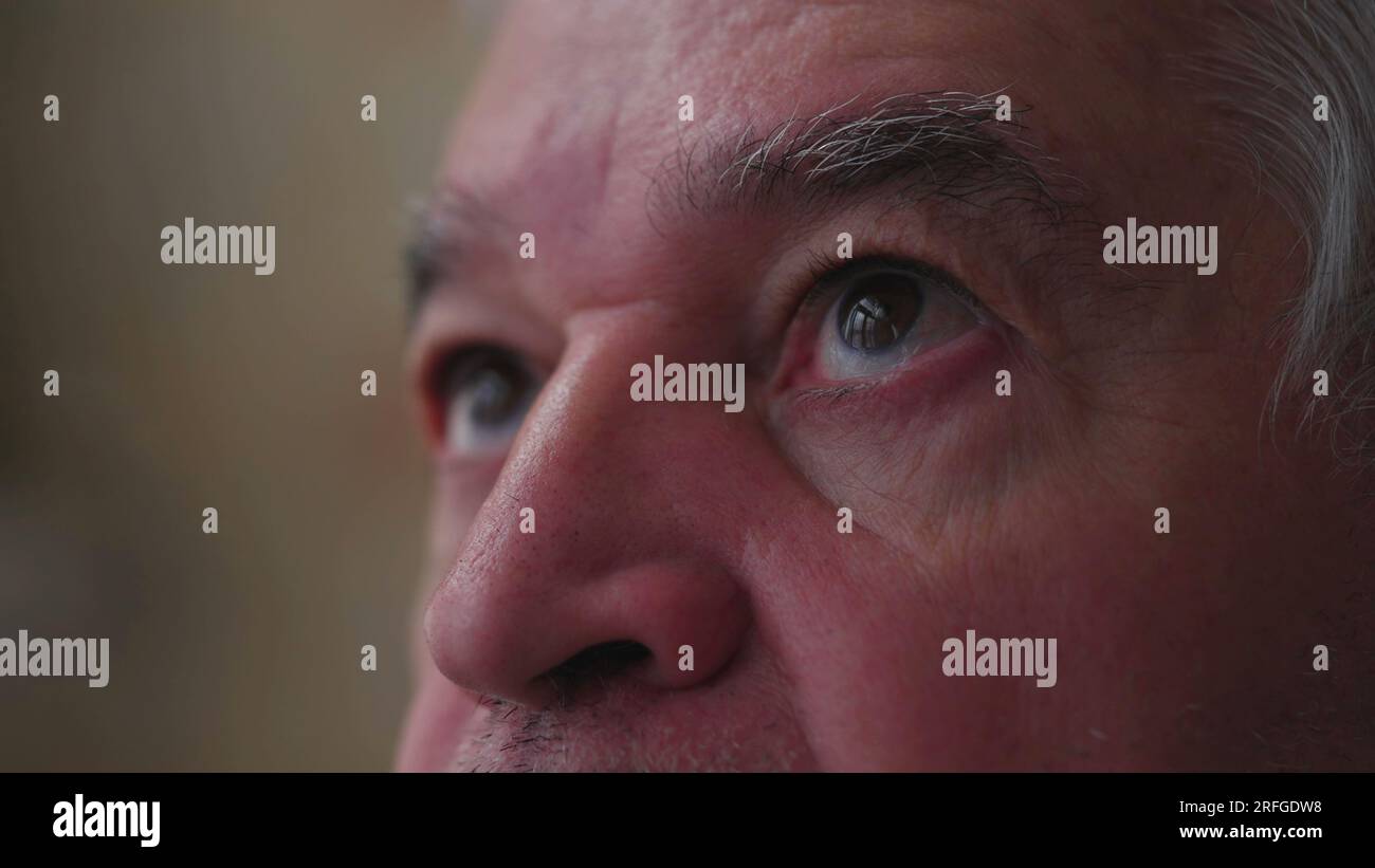 Close-up eyes of a contemplative senior man staring out through window ...