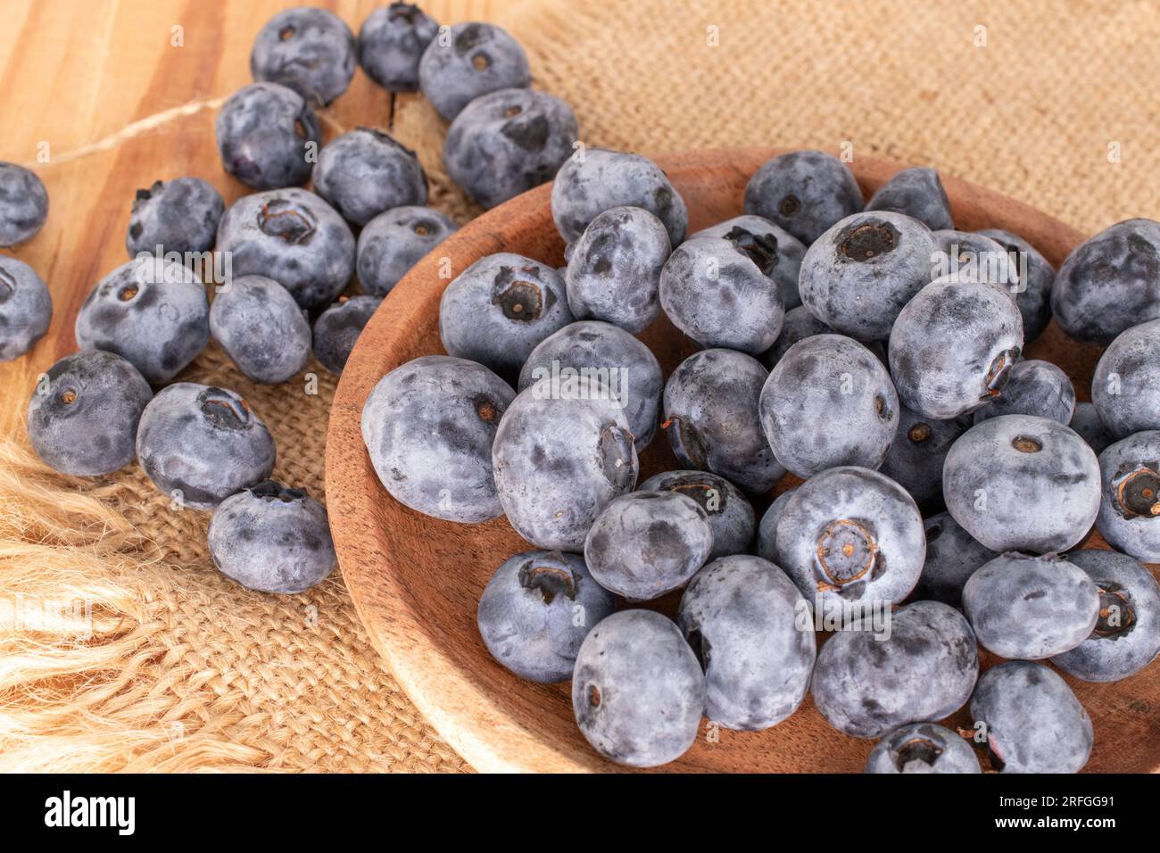 A few juicy blueberries in a wooden plate with a jute napkin on a ...