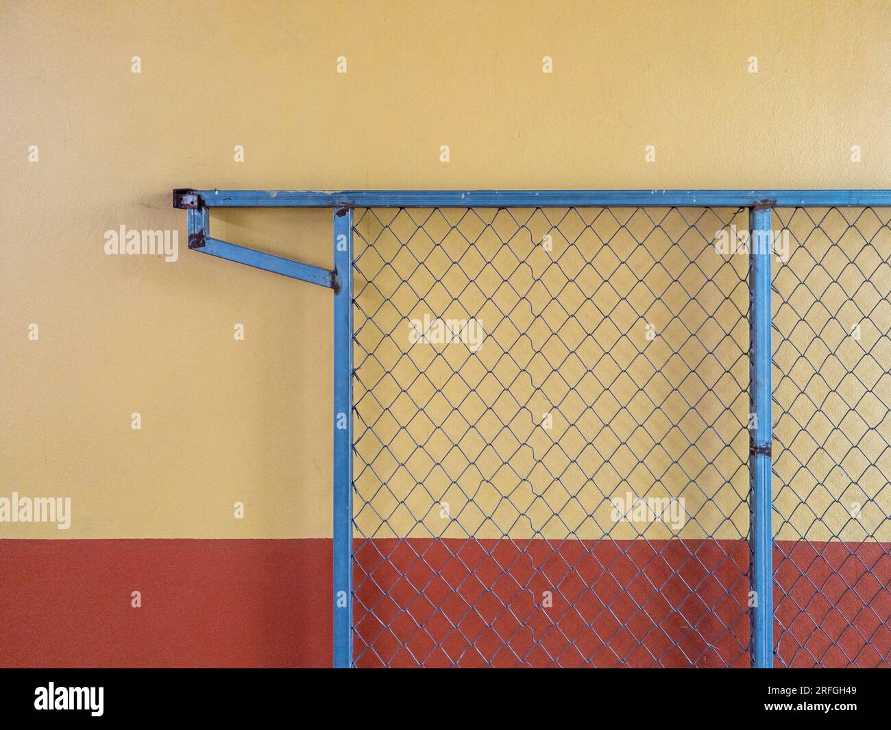 The old metal fence near the concrete wall of the rural primary school ...