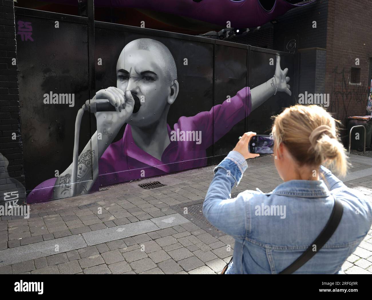 A person taking a photo of a mural of Sinead O'Connor by Artist ...