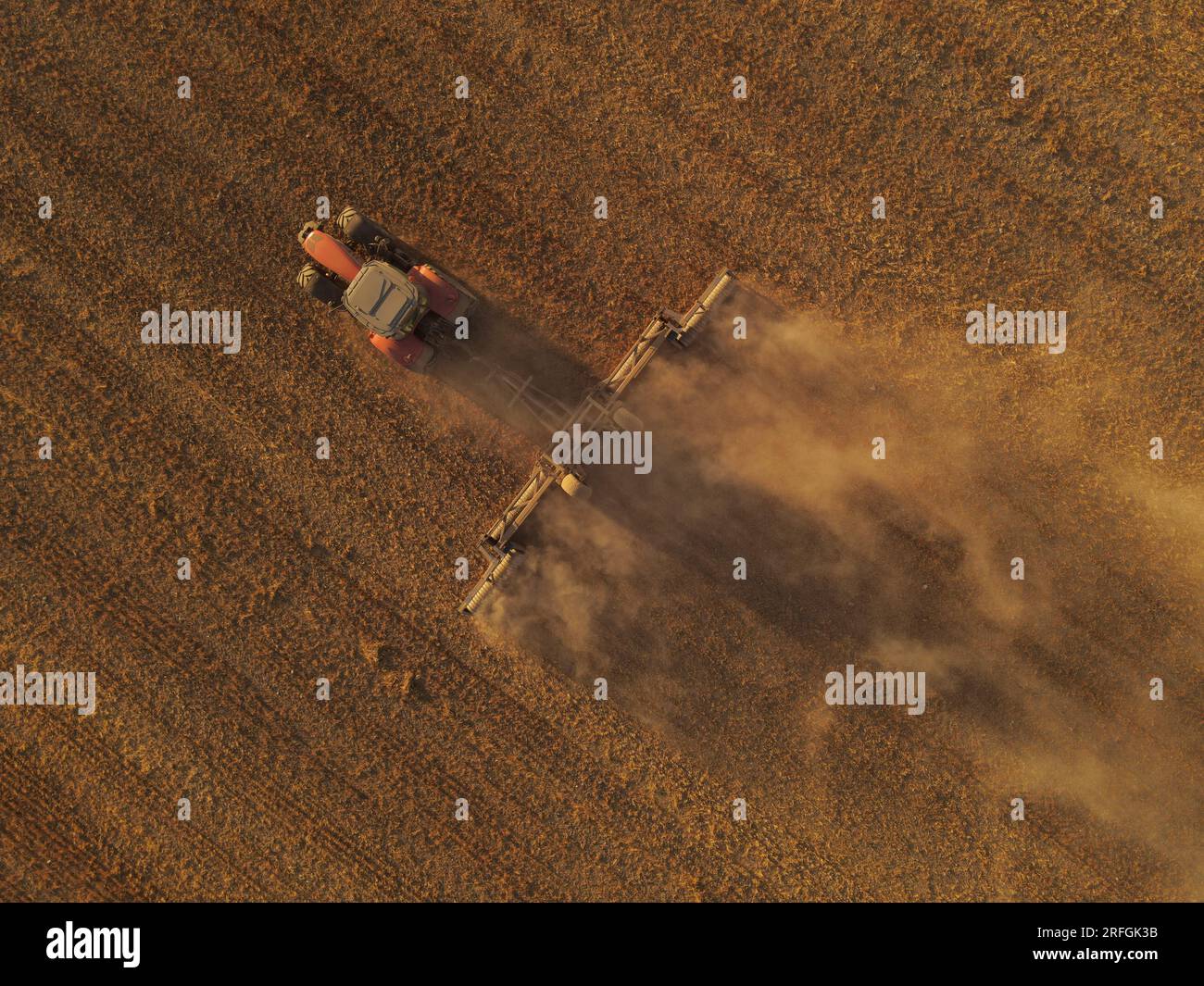 A Massey Ferguson Tractor, seen from above, cultivates a field after an ...