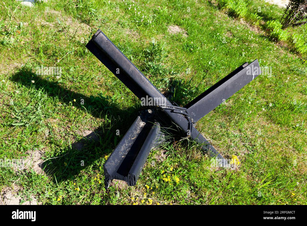 anti tank metal fortifications and hedgehogs on green grass, pieces of ...