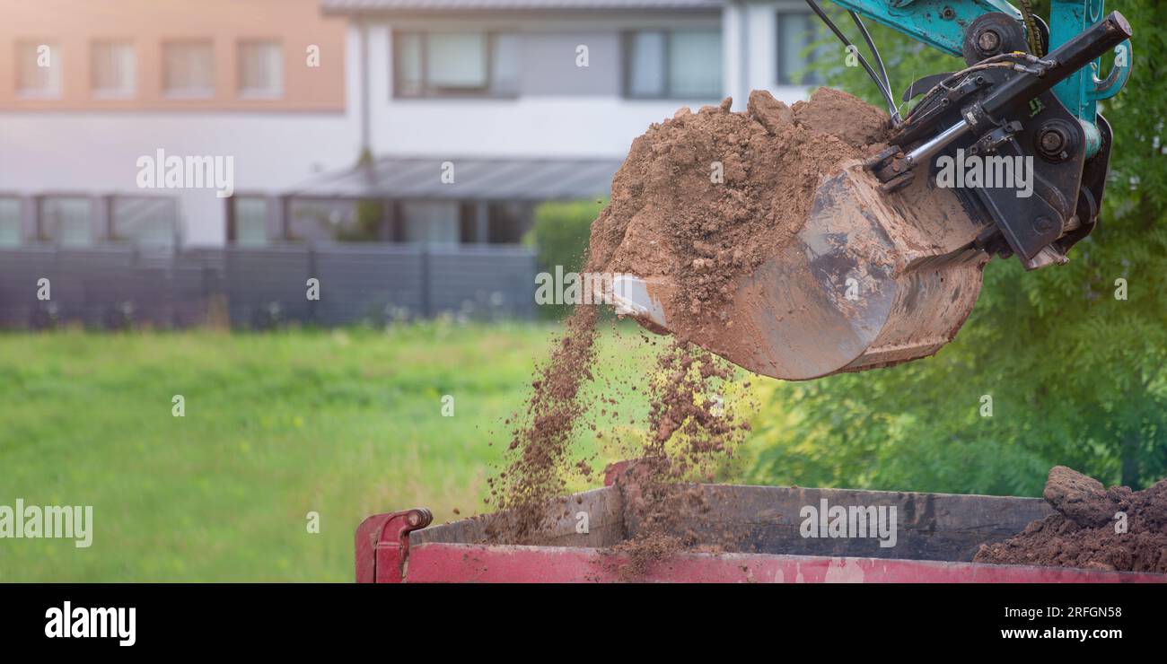A bucket of excavator pours the ground into a heap against the ...