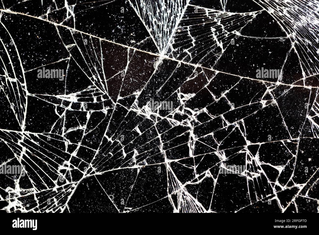 broken dirty glass with lots of damage and cracks on a black background ...