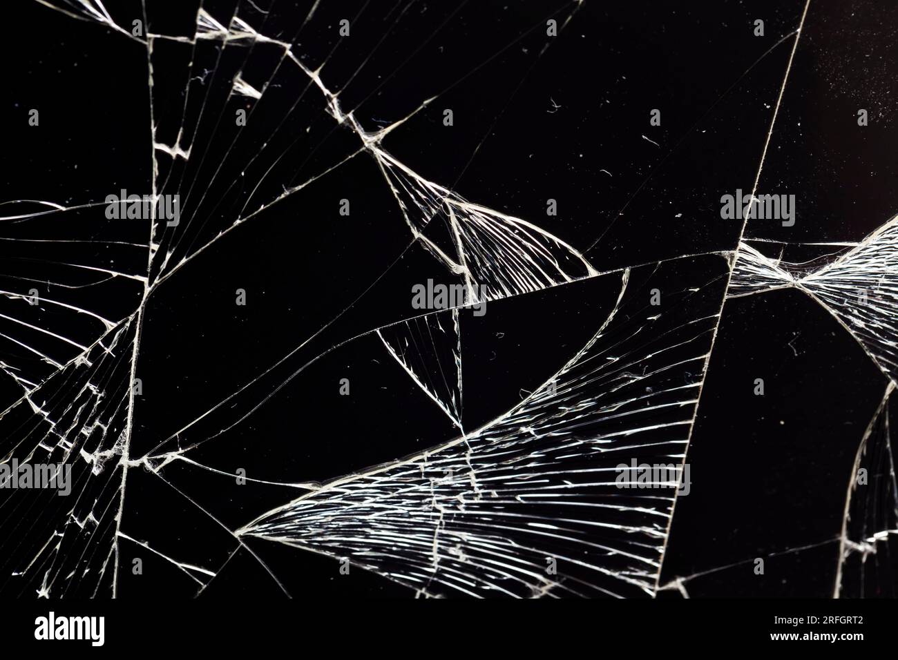 broken dirty glass with lots of damage and cracks on a black background ...