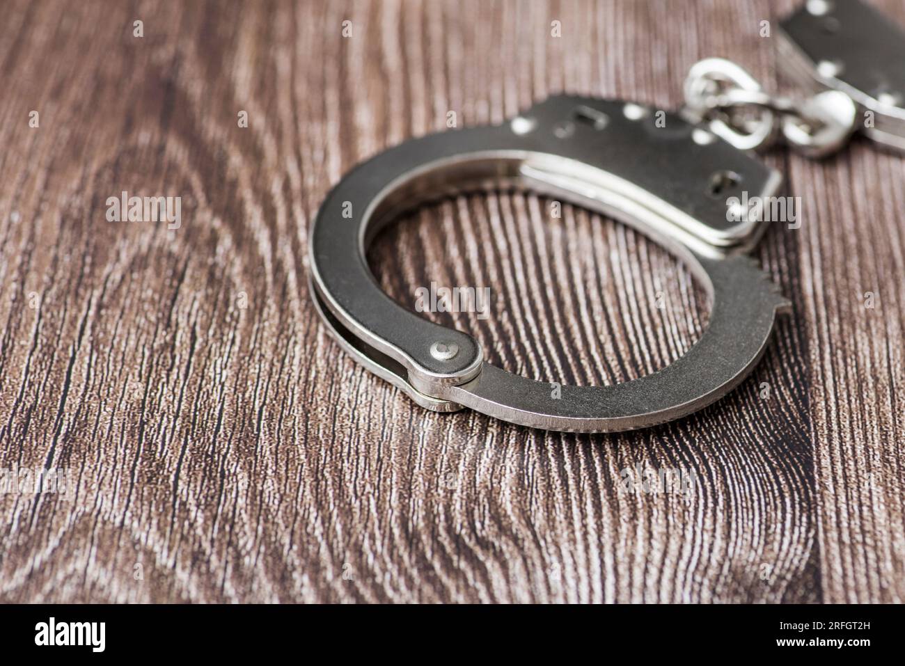 The metal handcuffs on wooden background. Handcuff or shackle. Police ...