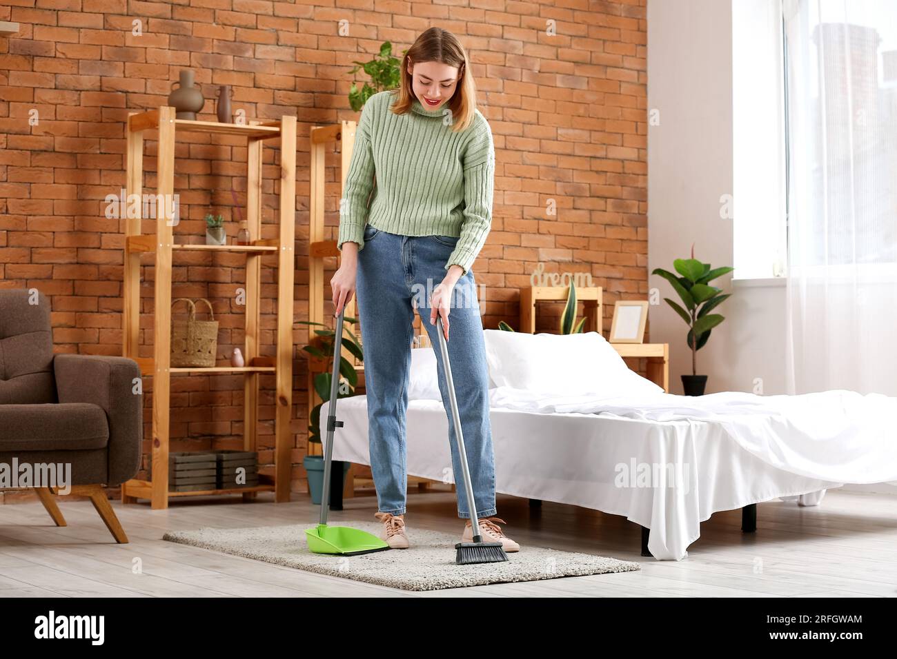 Young woman sweeping floor in bedroom Stock Photo - Alamy