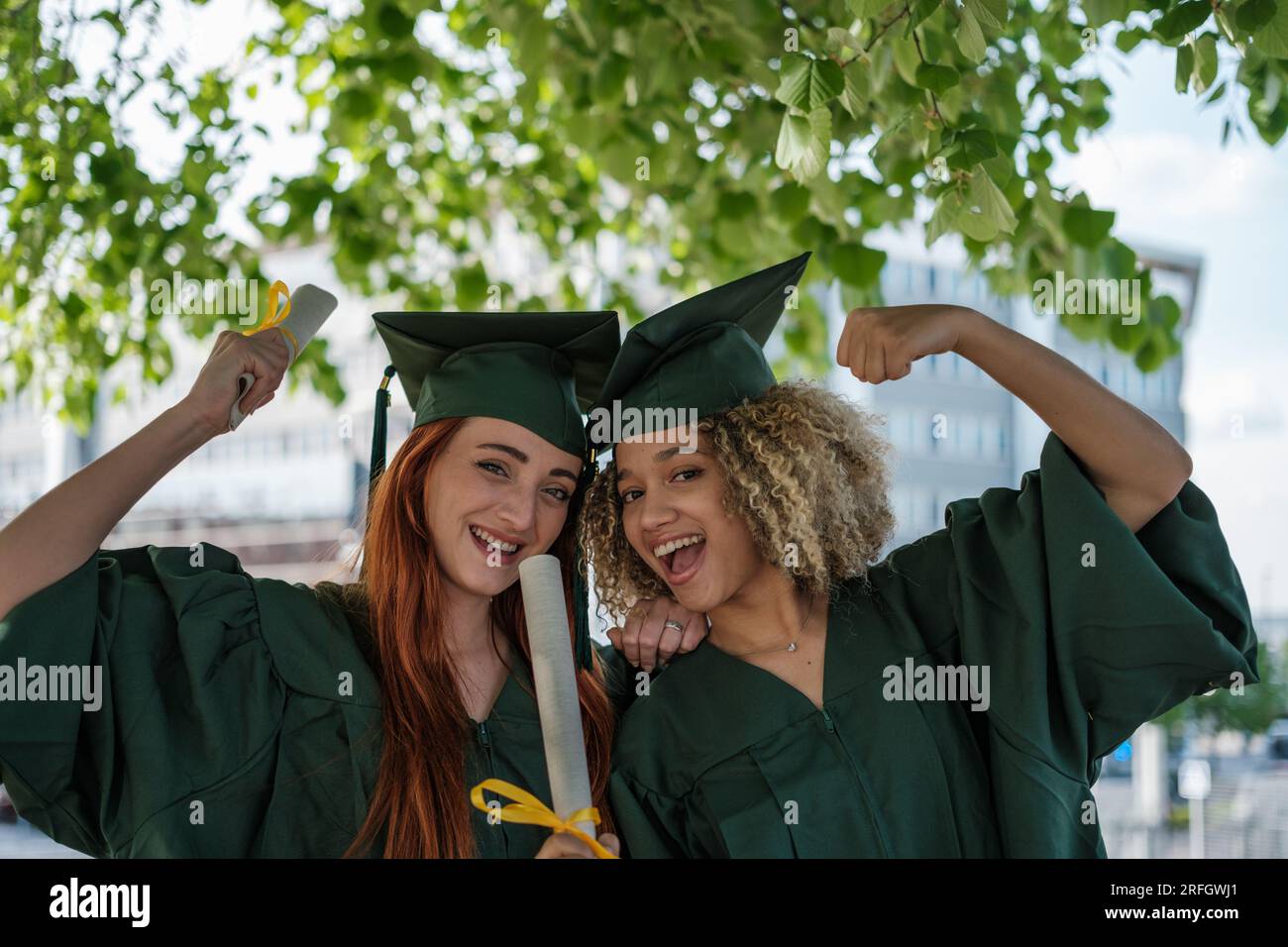 Two young students proud with their new university degree on graduation ...