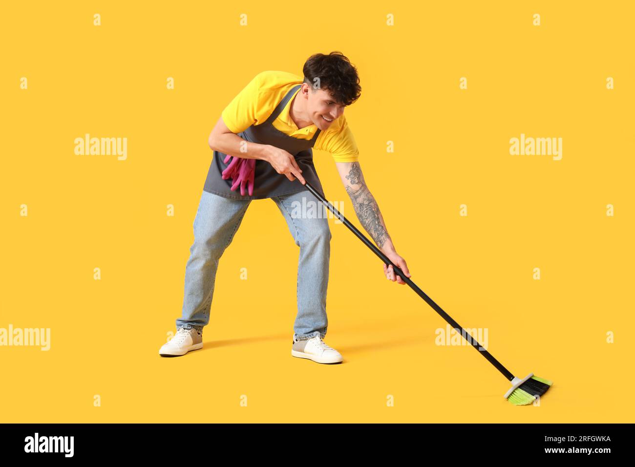 Male janitor with broom on yellow background Stock Photo - Alamy