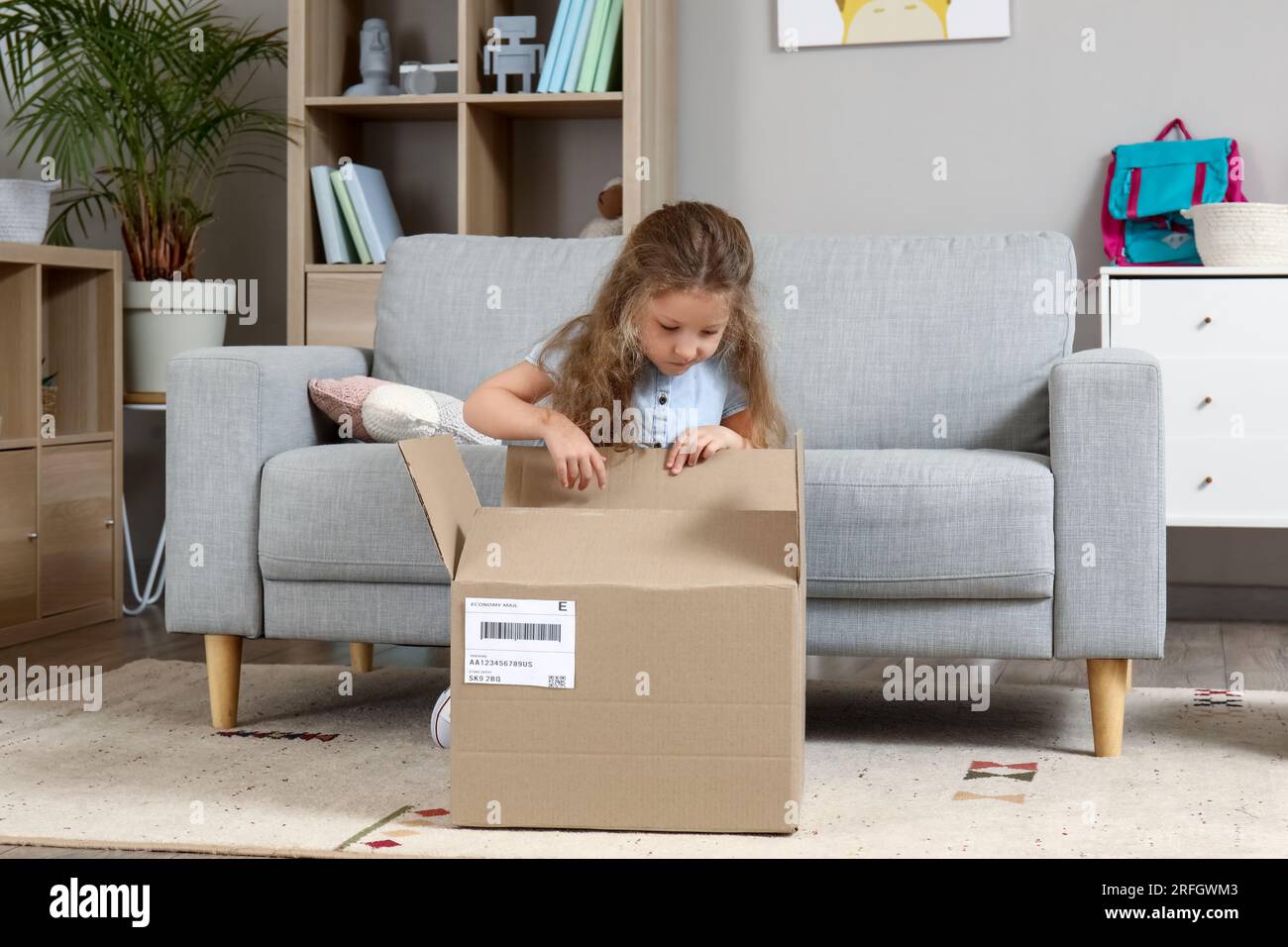 Cute little girl unpacking parcel at home Stock Photo - Alamy