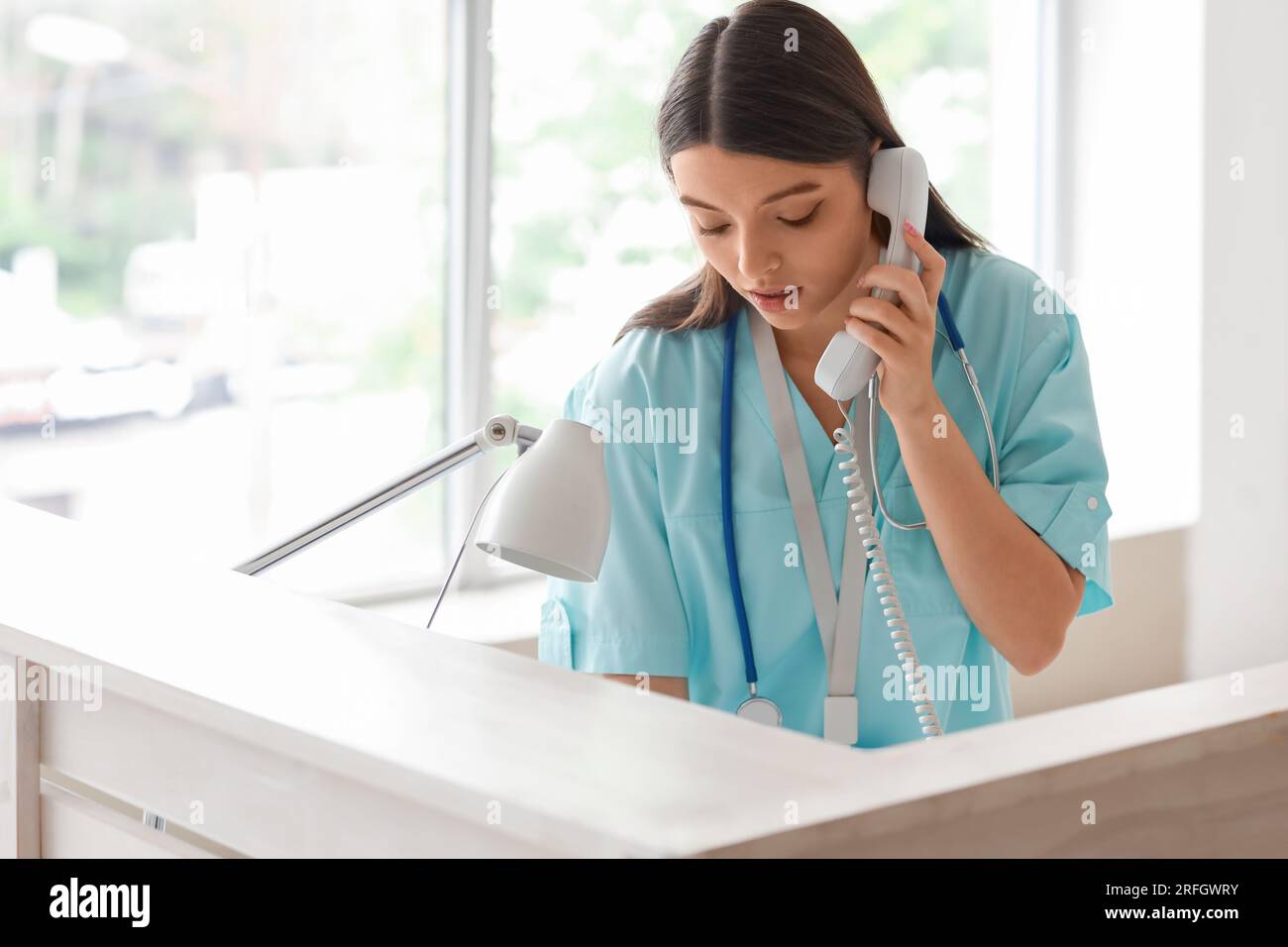 Female medical intern talking by telephone at reception in clinic Stock ...