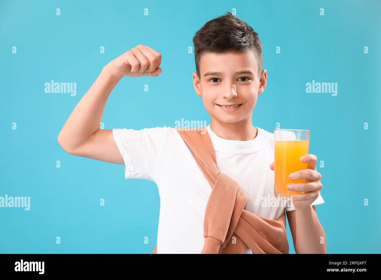 Little boy with glass of orange juice showing muscles on blue ...