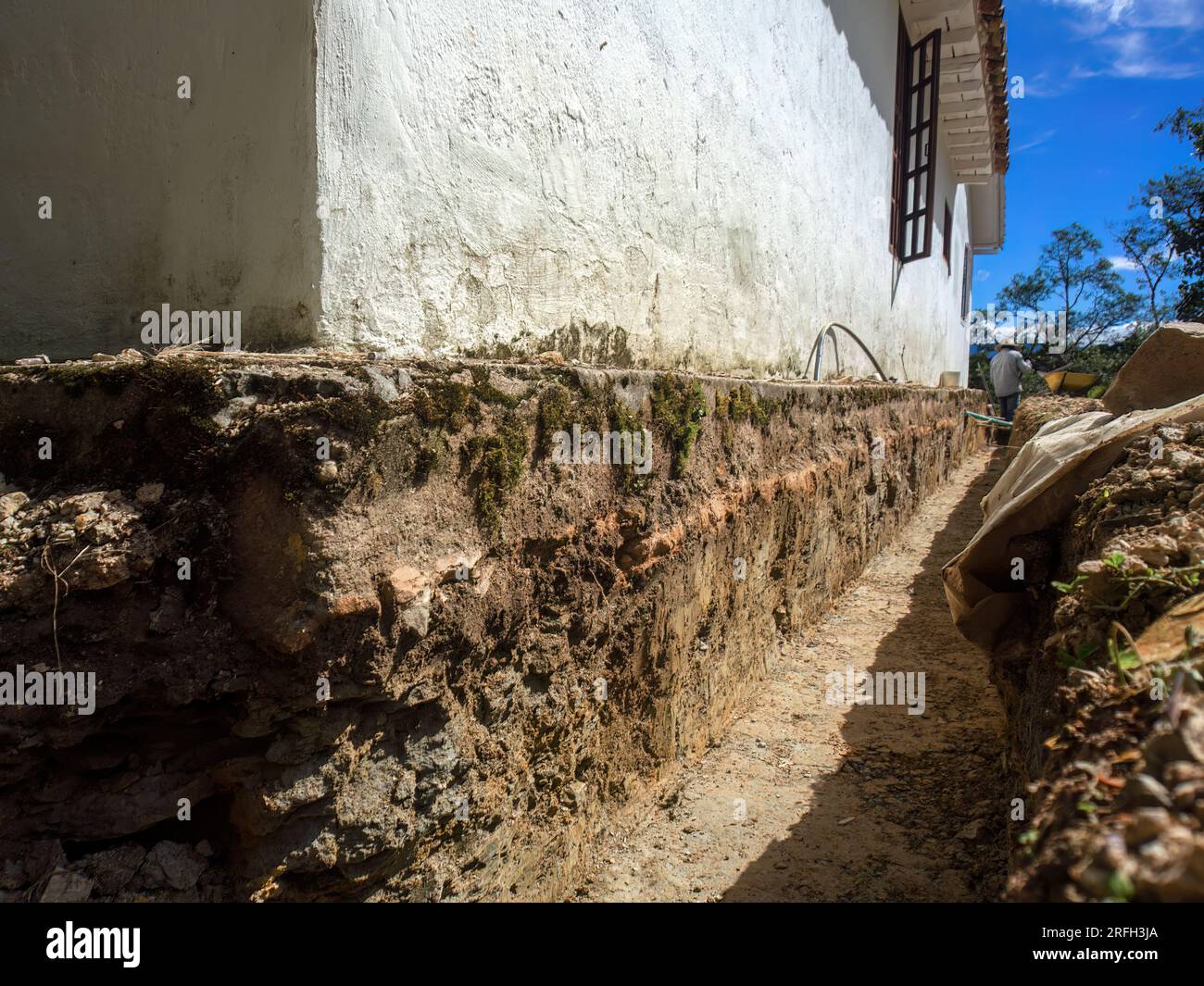 A man digging a ditch for rain water management in a farmhouse, in the ...