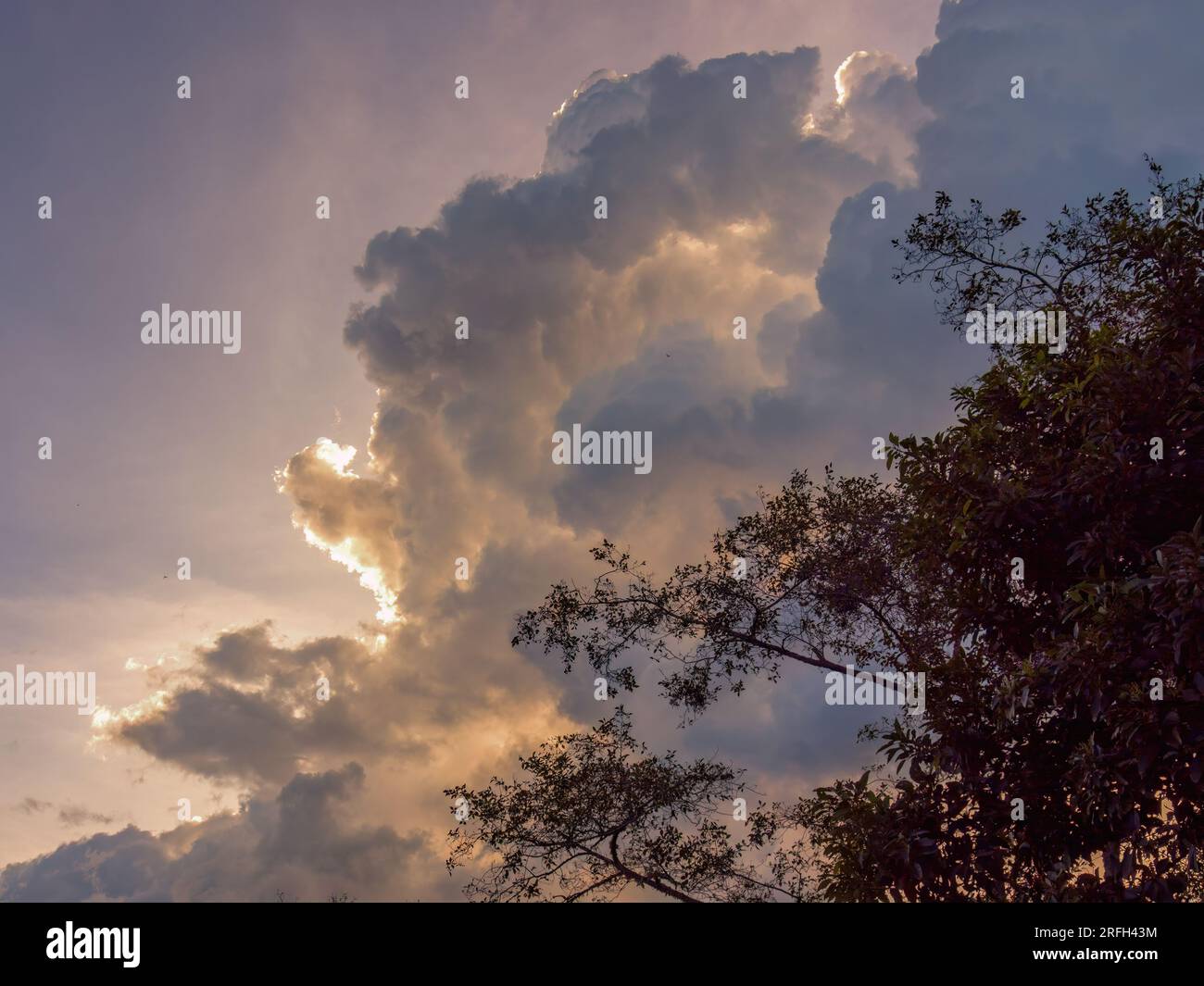 The sun hidden behind dense cumulus clouds, up in the sky above the eastern Andean mountains of ...
