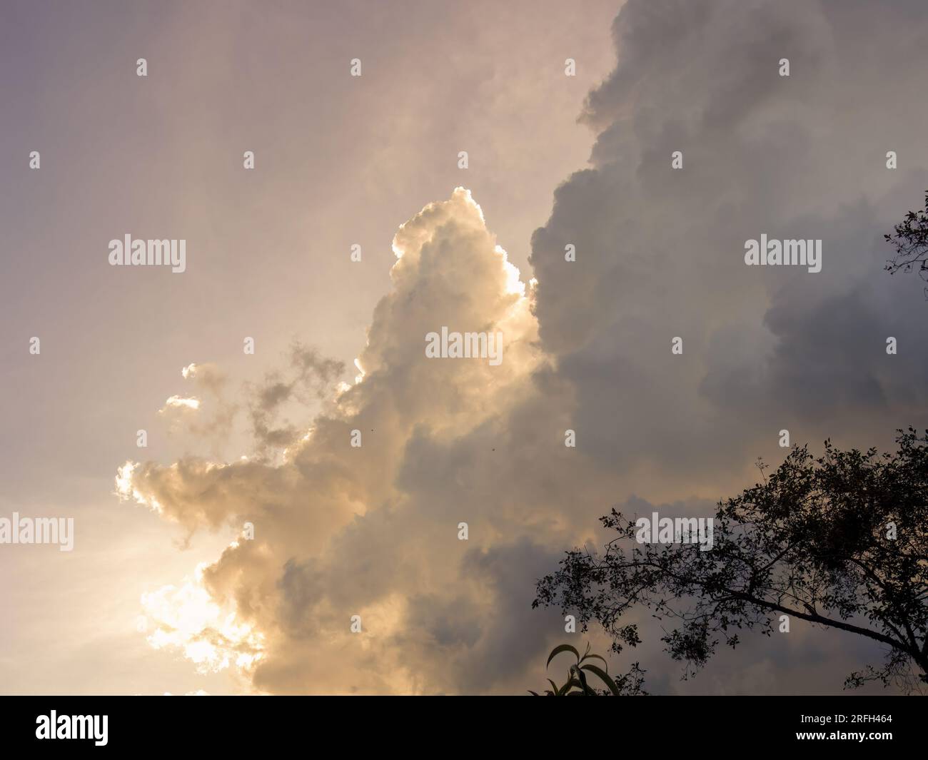 The sun hidden behind dense cumulus clouds, up in the sky above the eastern Andean mountains of ...