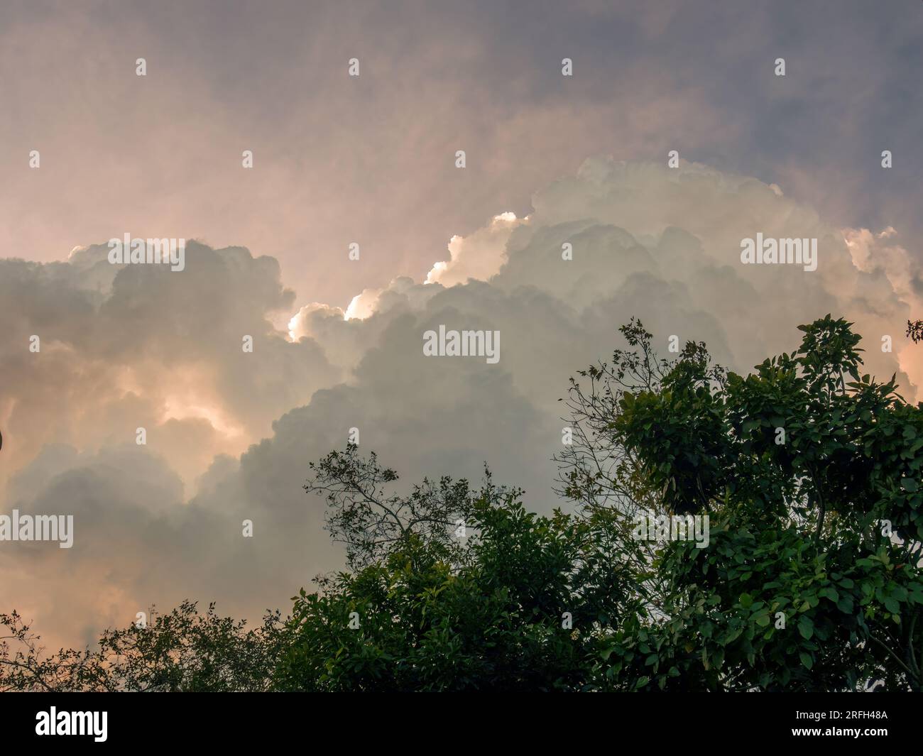 The sun hidden behind dense cumulus clouds, up in the sky above the eastern Andean mountains of ...