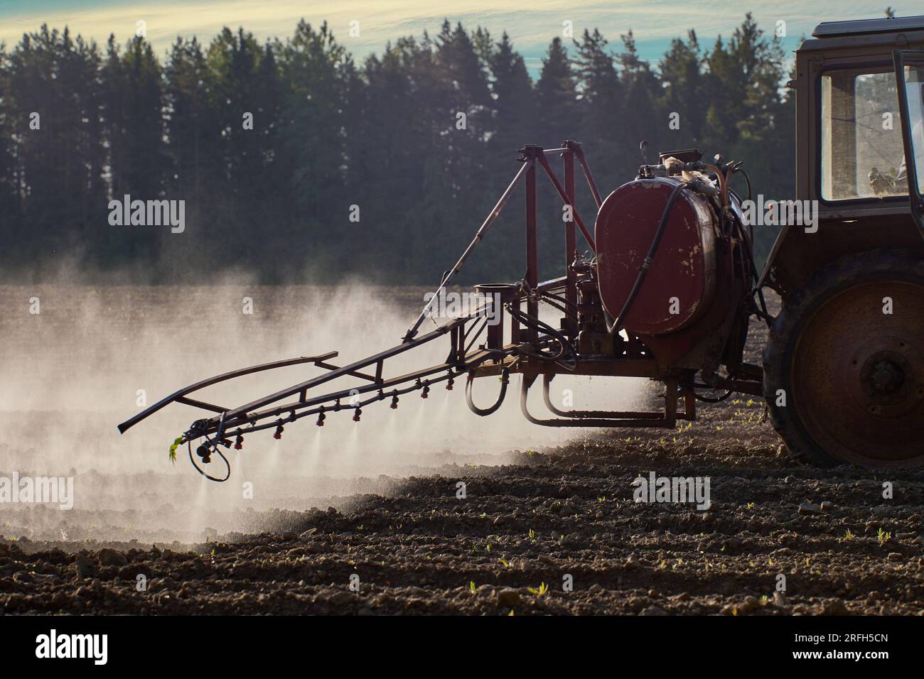Spraying crops with chemicals such as pesticides or herbicides using sprayer mounted on wheeled ...