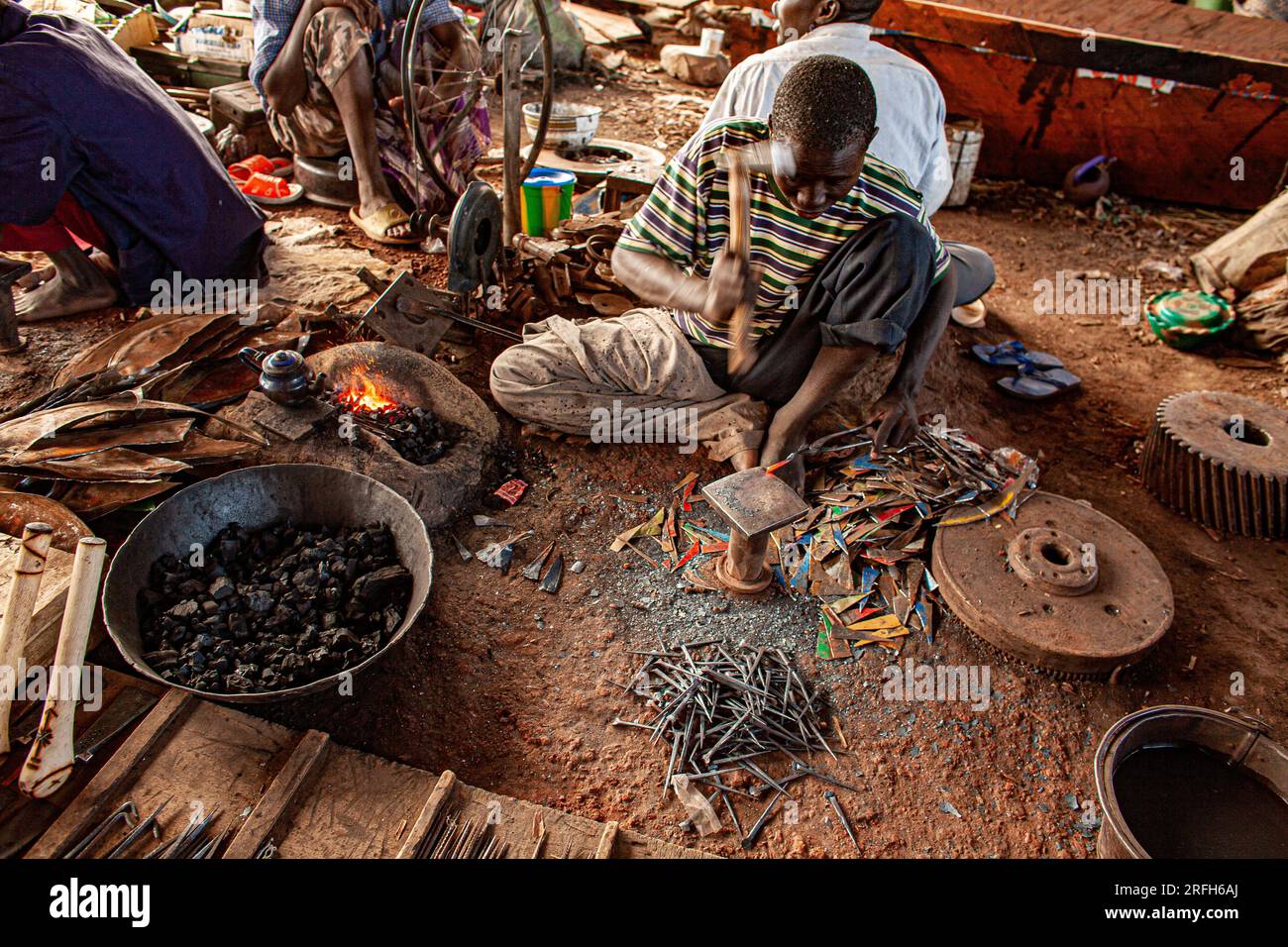 African blacksmith craft nails from scrap metal using a hammer . Boat ...