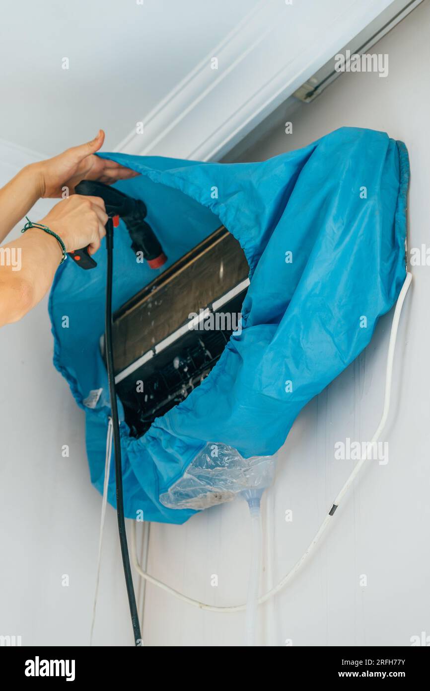 Serviceman cleans indoor unit of air conditioner using pressurized ...