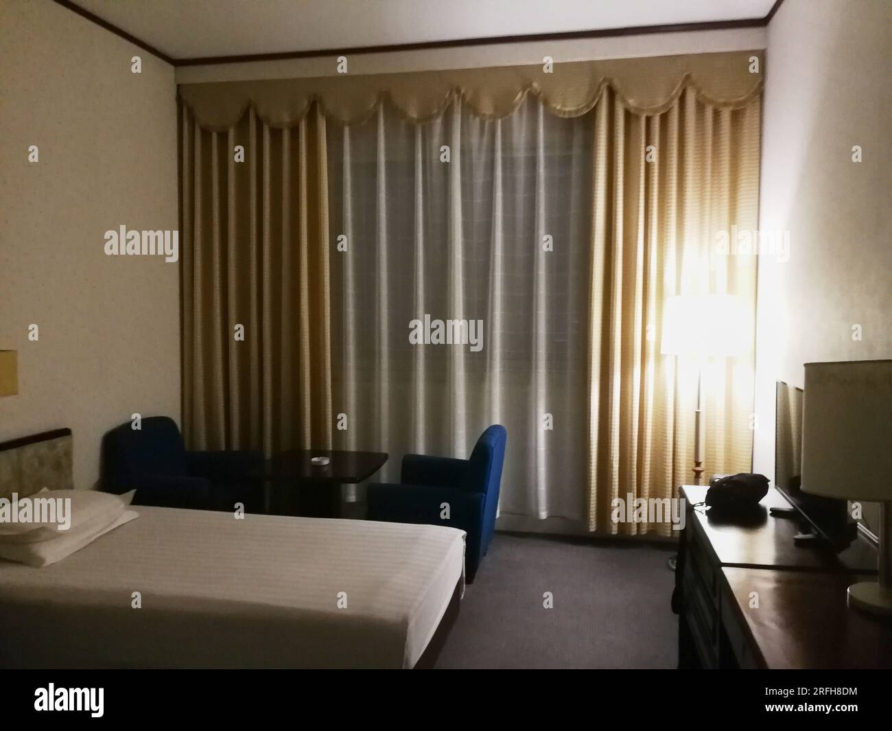 A hotel room with a bed, a desk, and a chair in the Yanggakdo ...