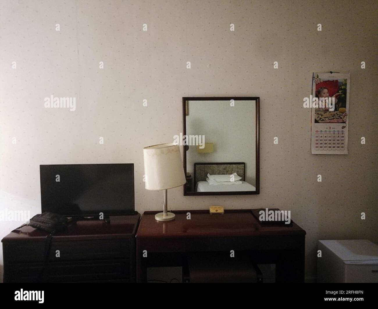 A hotel room with a bed, a desk, and a chair in the Yanggakdo ...