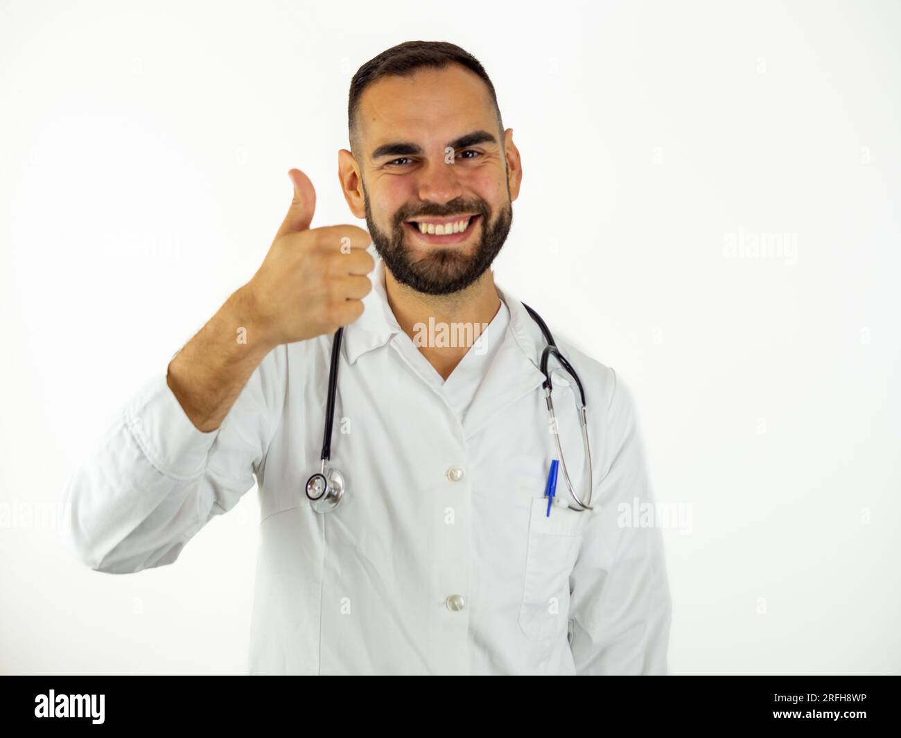 Young male doctor thumbs up while smiling. Looking at camera isolated ...