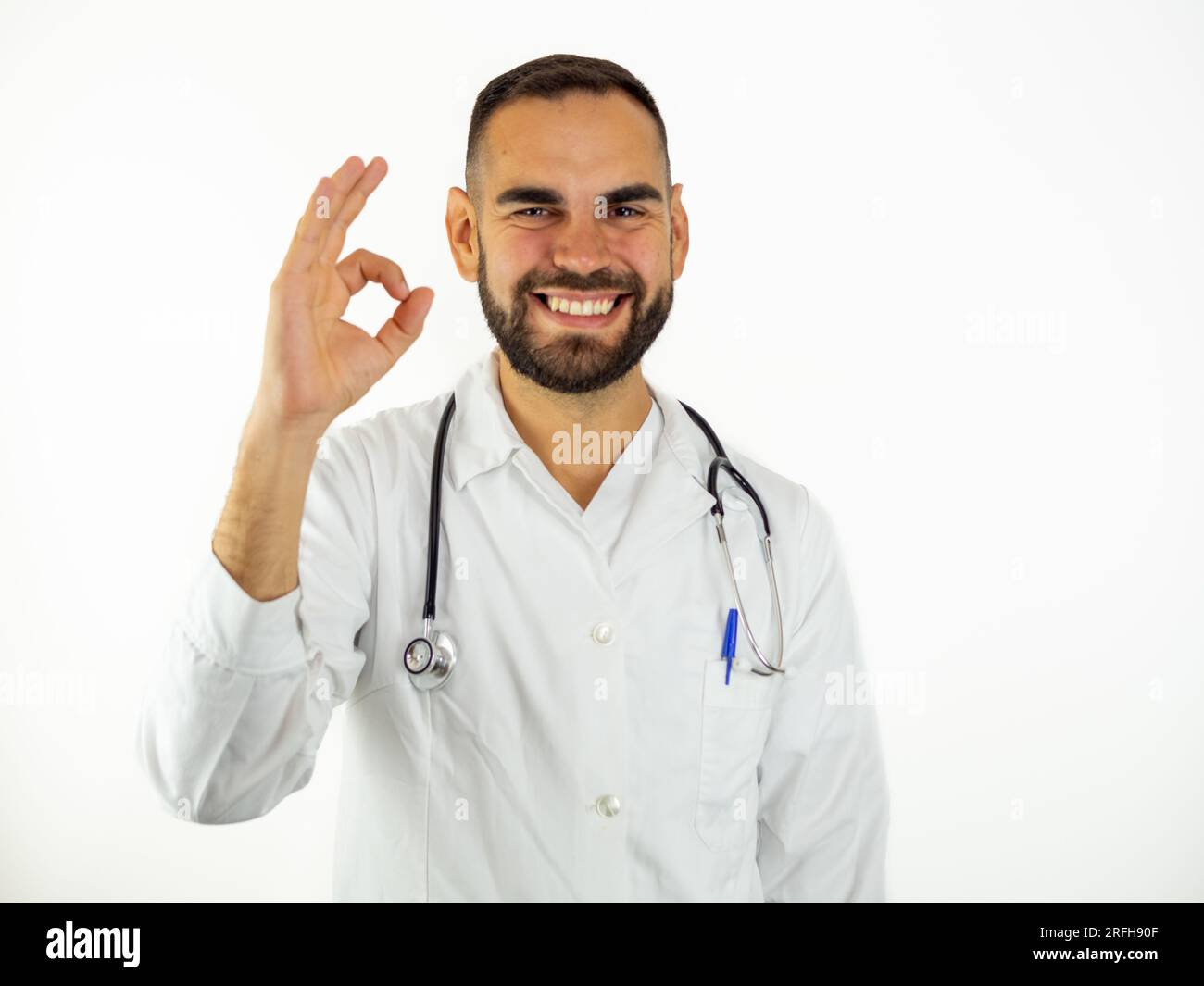 Young male doctor ok sign while smiling. Looking at camera isolated on ...