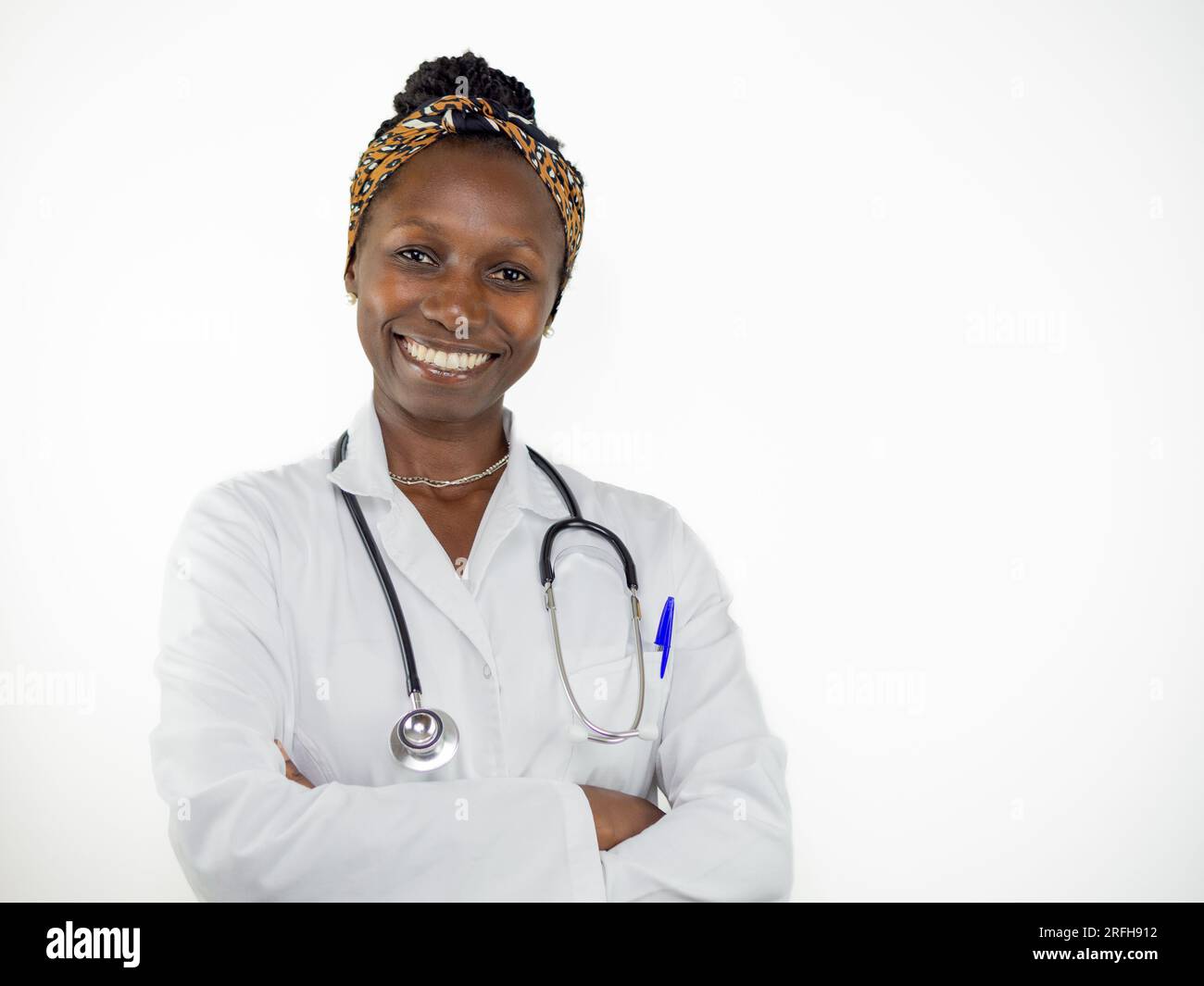Young female doctor crossing her arms while smiling. Looking at camera isolated on white ...
