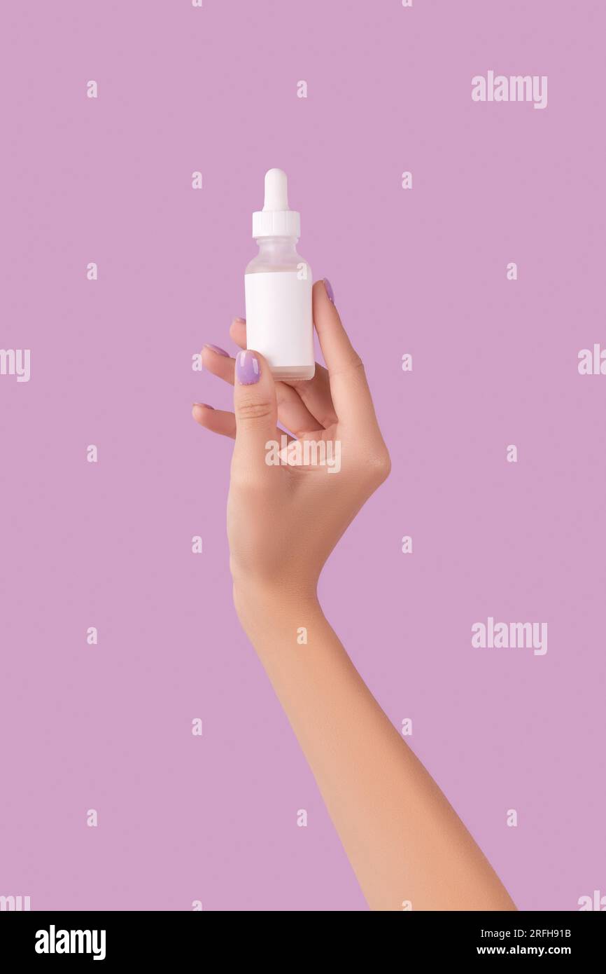 Womans hand holding dropper with serum on pastel lavender background ...